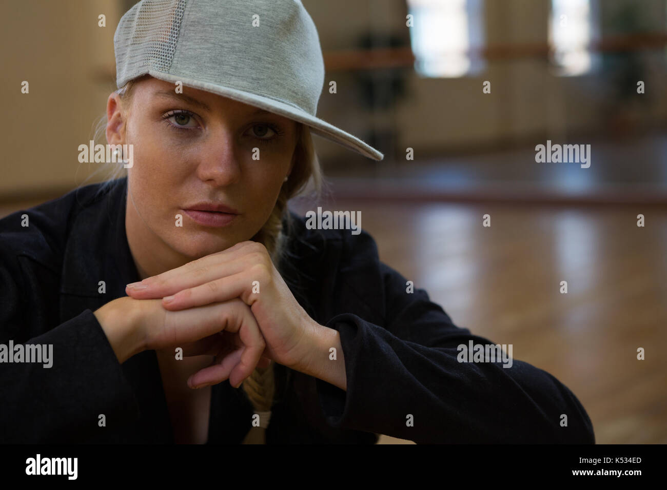 Portrait of young female dancer wearing cap on floor in studio Stock ...