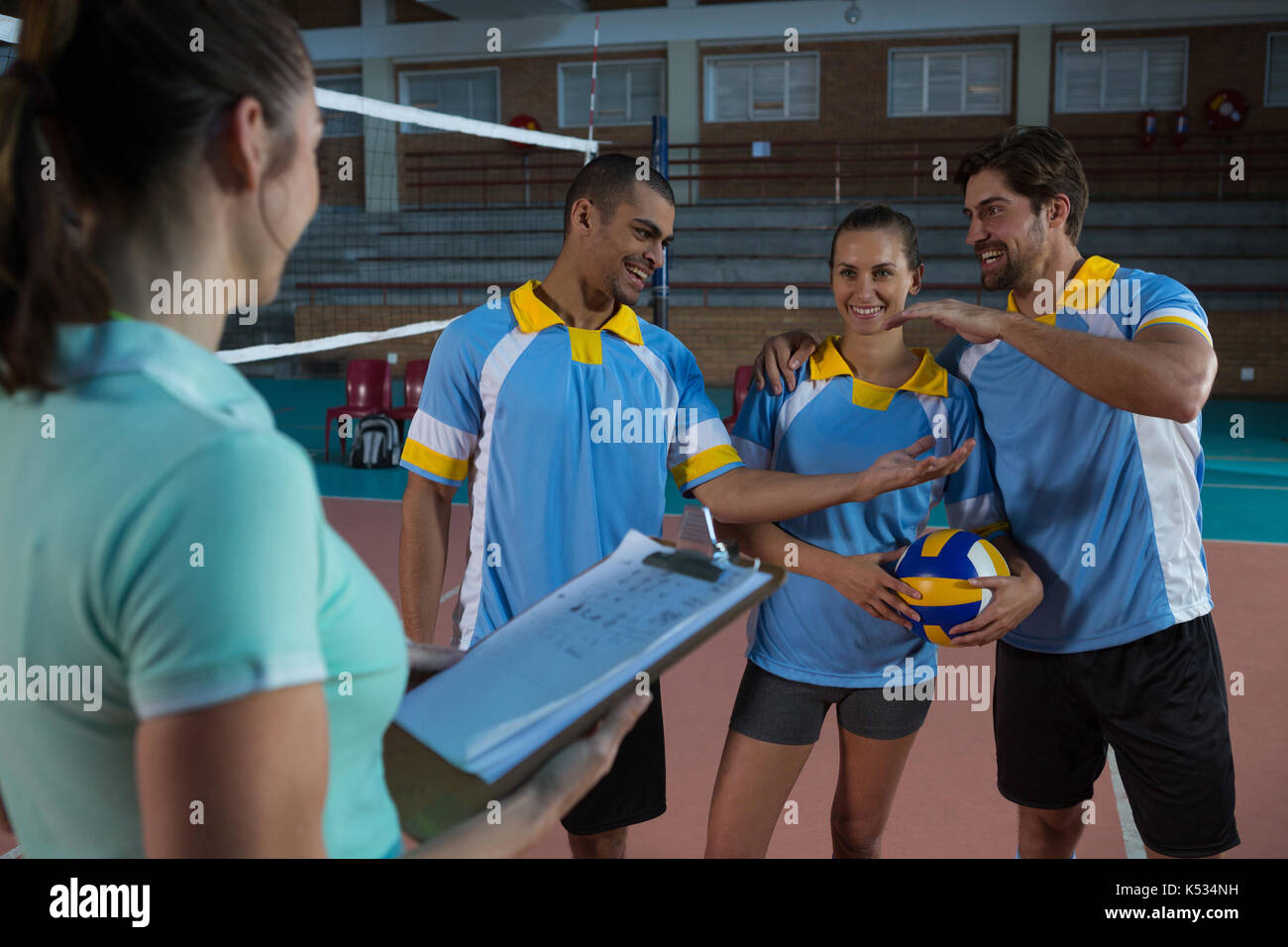 Female coach with happy volleyball players standing at court Stock ...