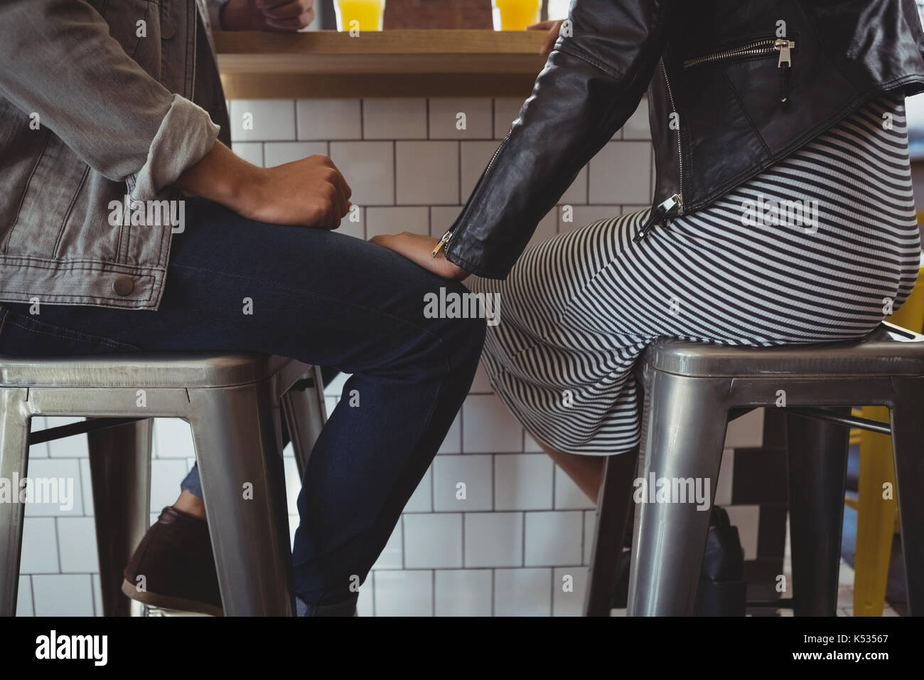 Low section of couple sitting on stool at counter in cafe Stock Photo ...