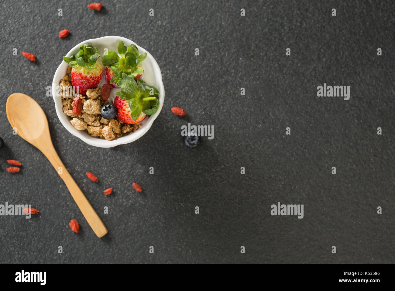 Bowl of breakfast cereals and fruits with spatula on black background ...