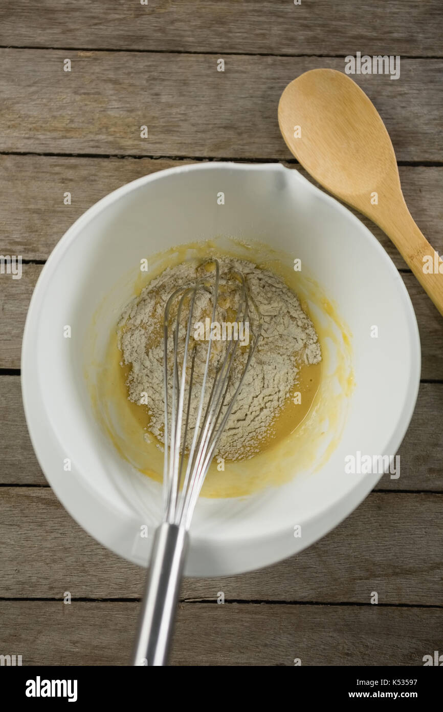 Overhead view of egg and flour batter in bowl on wooden table Stock ...