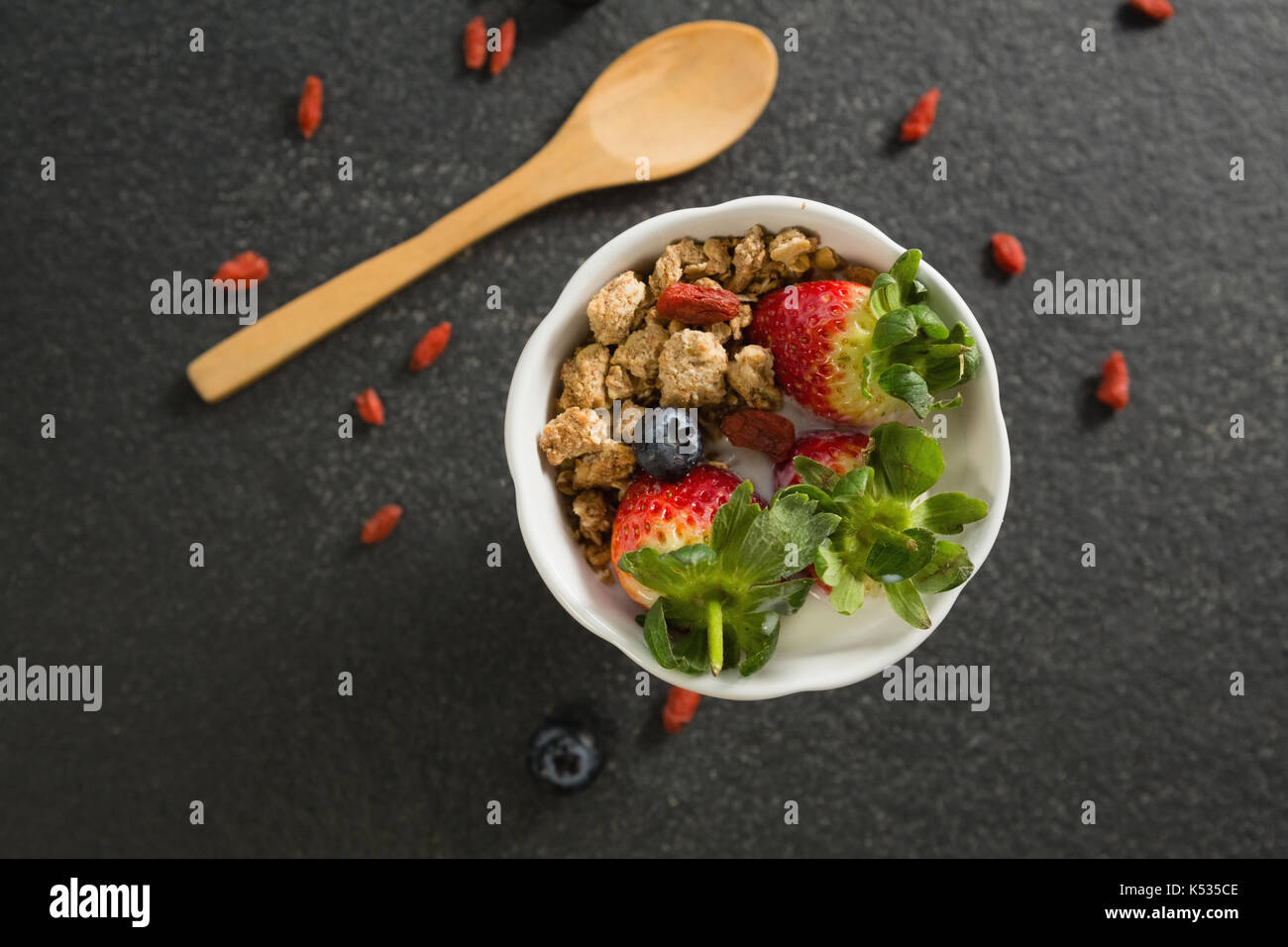Bowl of breakfast cereals and fruits with spatula on black background ...