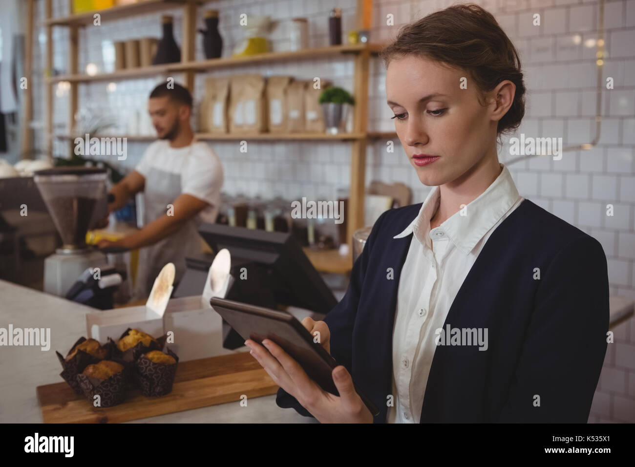 Female owner using digital tablet with waiter working in cafe Stock ...