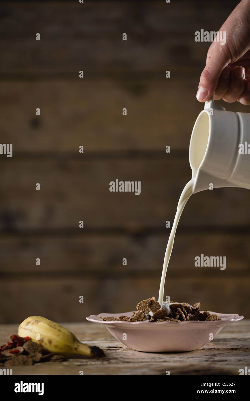 Close-up of hand pouring milk on wheat flakes Stock Photo - Alamy