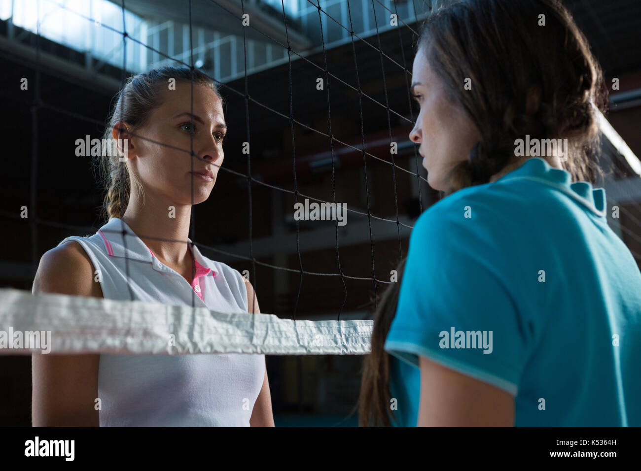 Aggressive female volleyball players looking each other through net ...