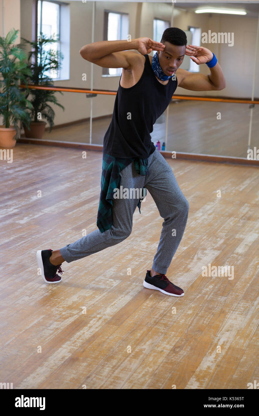 Full length of male dancer practicing against mirror on floor at studio ...