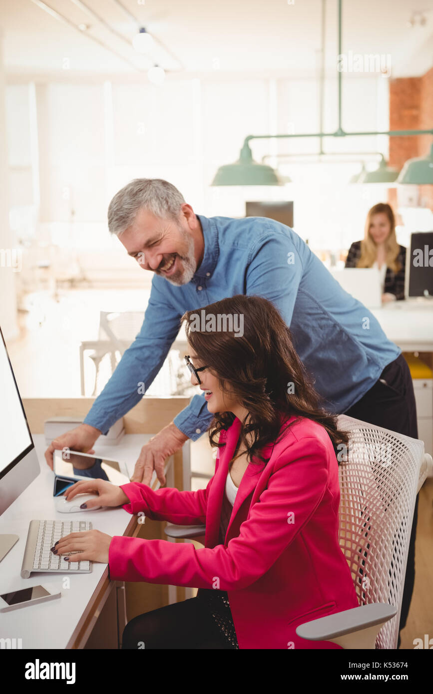 Happy executives interacting with each other while working at desk in office Stock Photo - Alamy