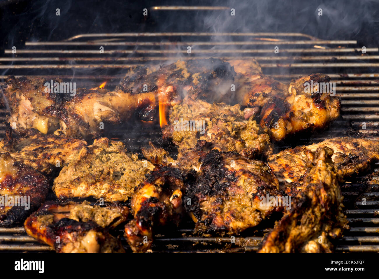 Grilling traditional Jamaican spicy jerk chicken with over wood fire ...