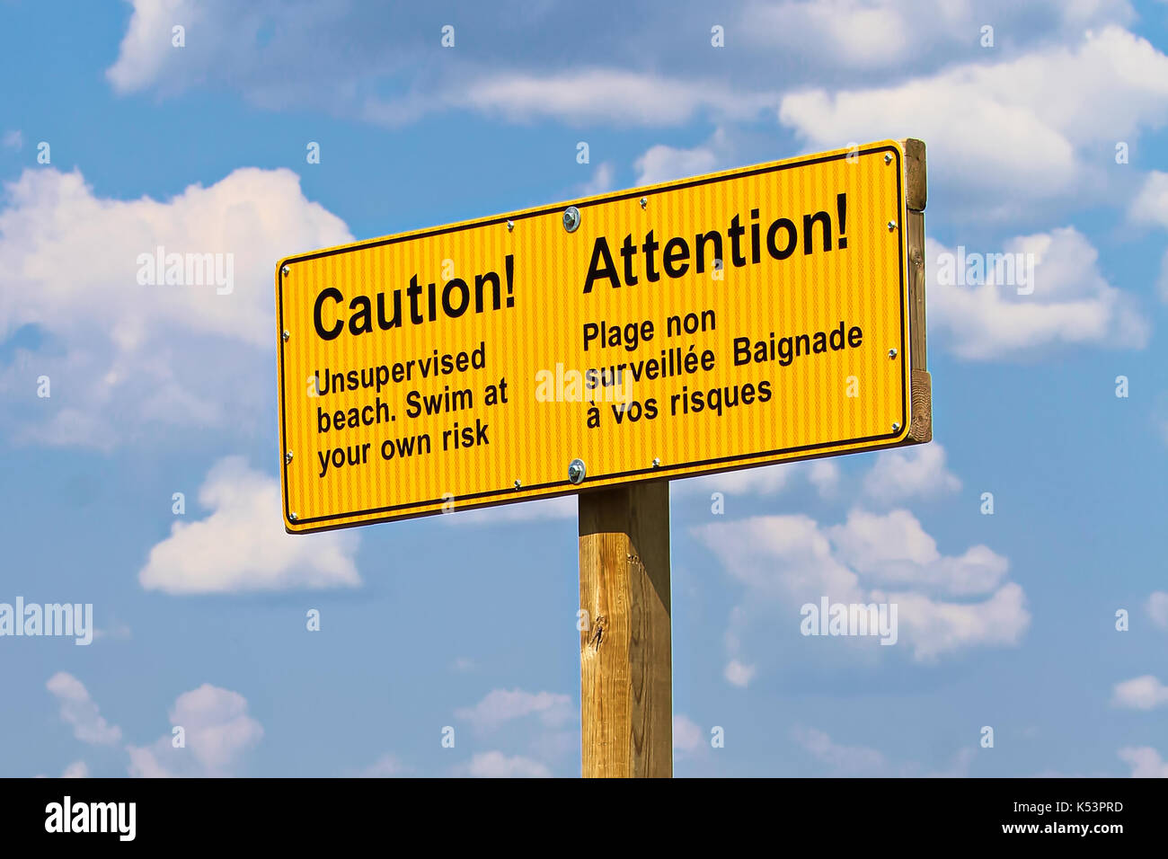 A yellow caution unsupervised beach sign in french and english Stock ...