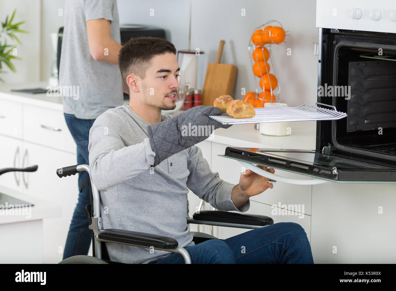 young disabled man on wheelchair put pastry in the oven Stock Photo - Alamy