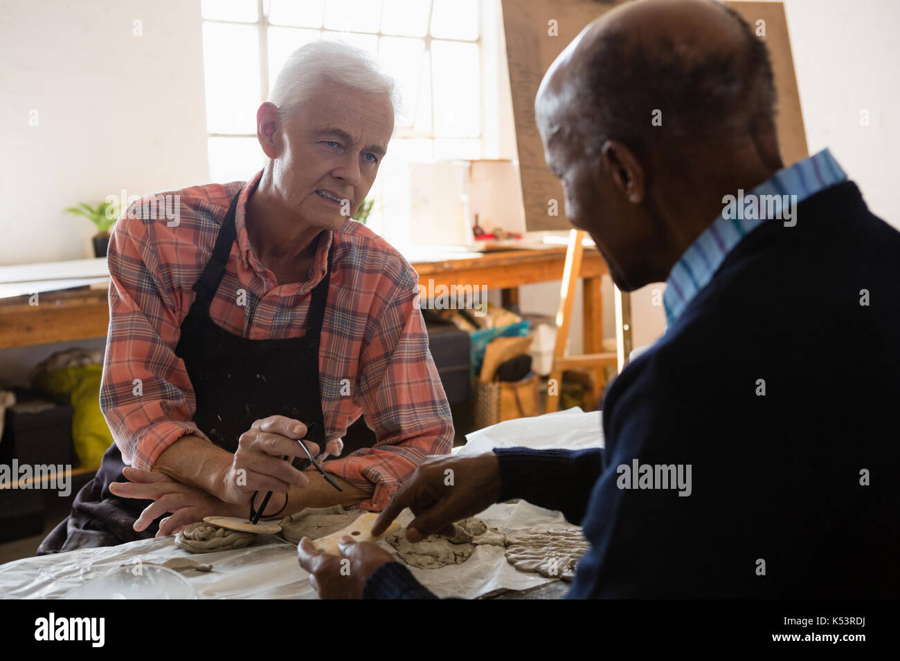 Senior artist assisting man table in art class Stock Photo - Alamy