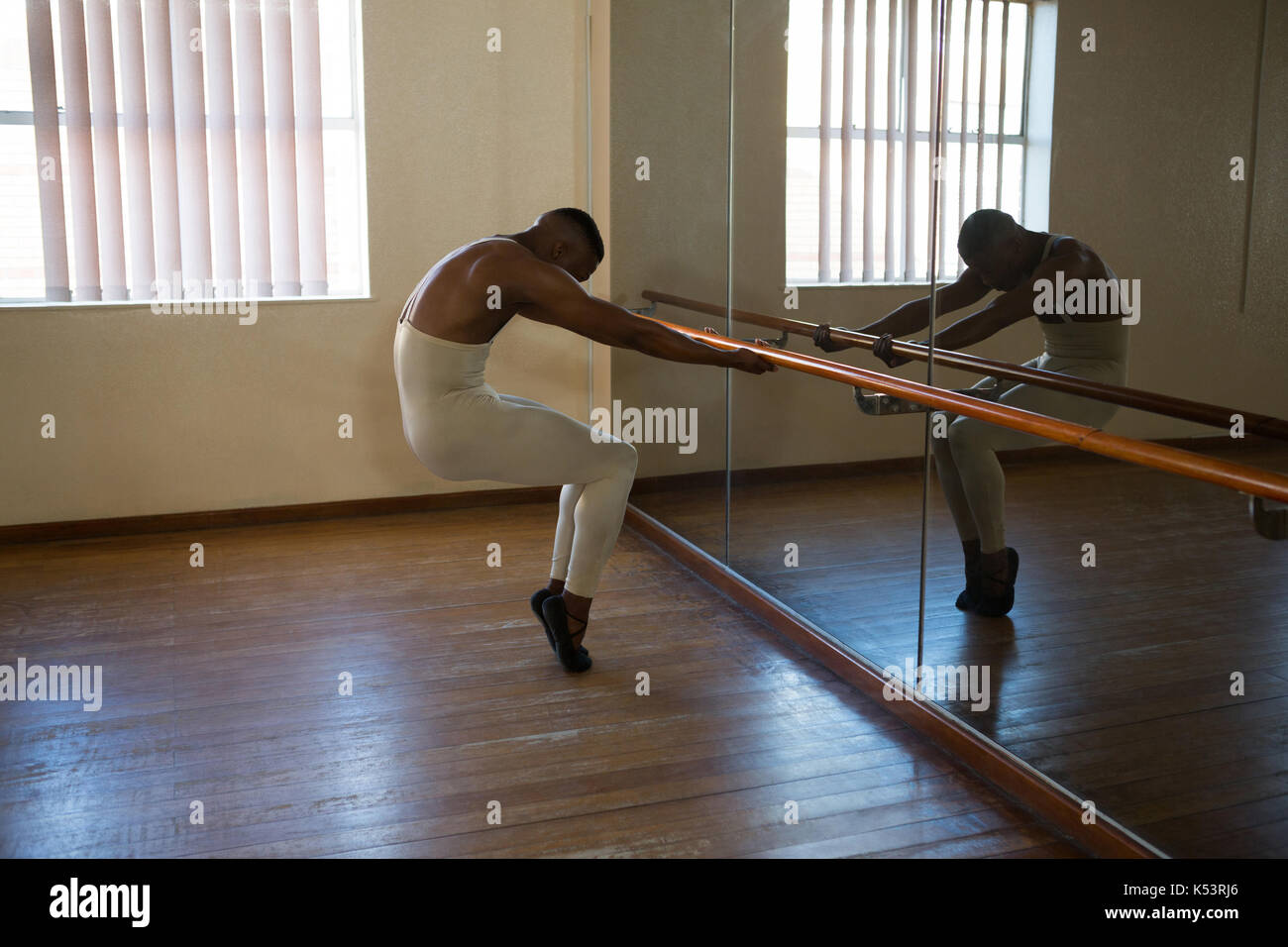Ballerino stretching on a barre while practicing ballet dance in the ...
