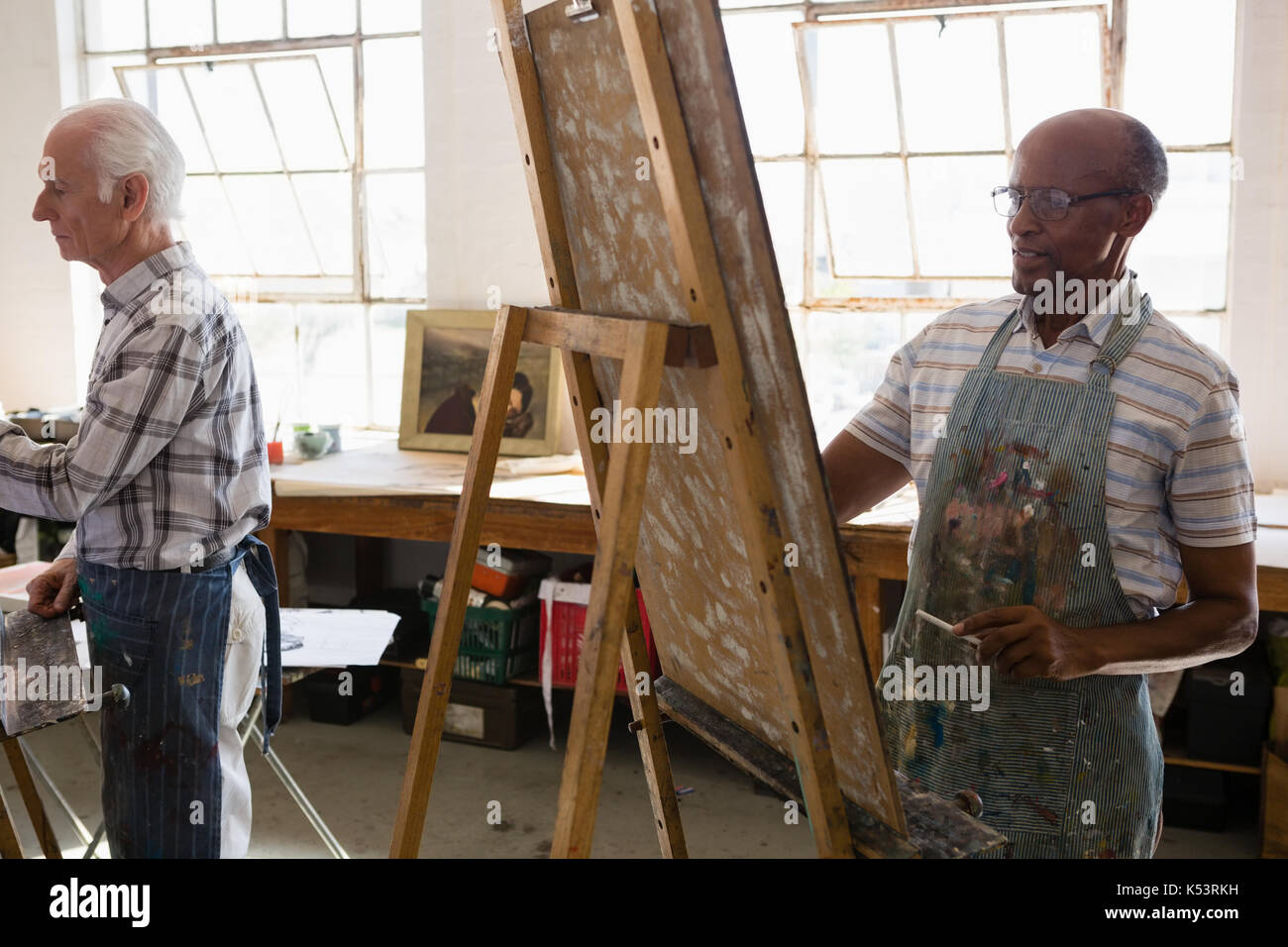 Senior males painting on easel while standing in art class Stock Photo ...