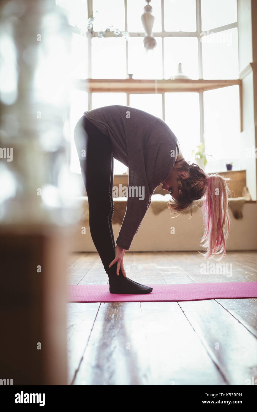 Side view of young woman bending while doing yoga on exercise mat Stock ...
