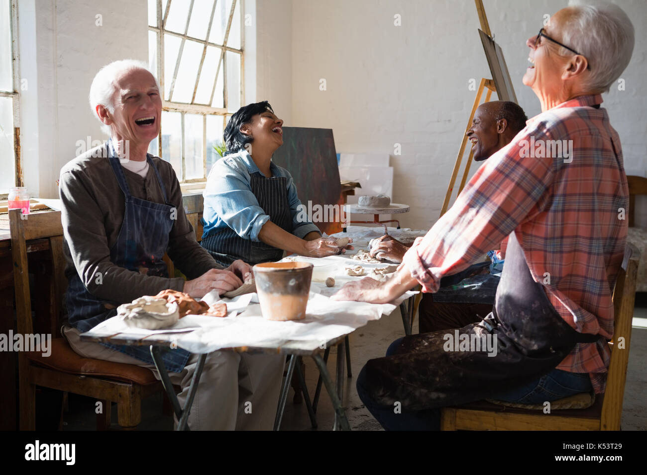 Cheerful senior friends at table by window in art class Stock Photo - Alamy