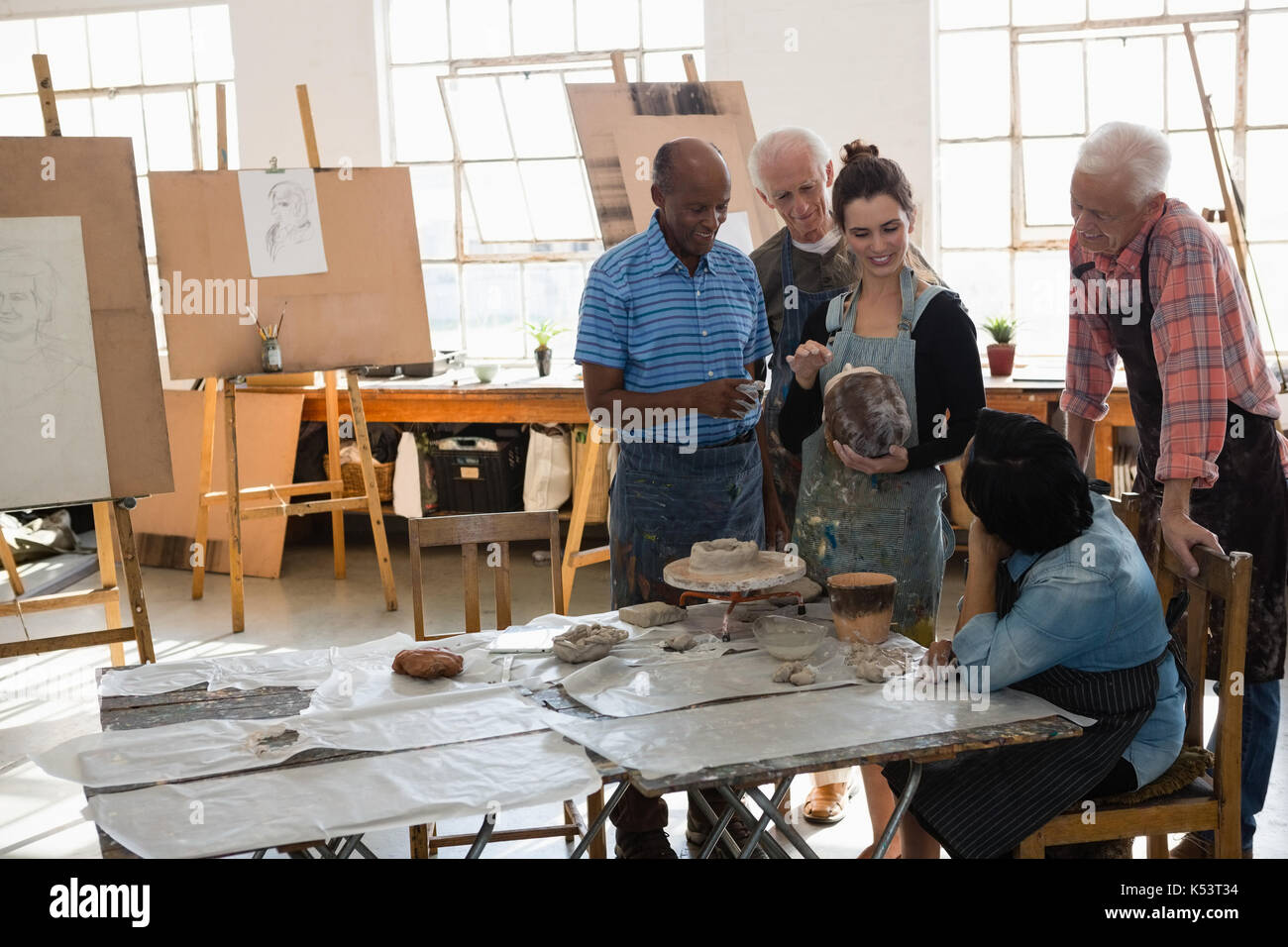 Female instructor holding sculpture while explaining senior people at ...