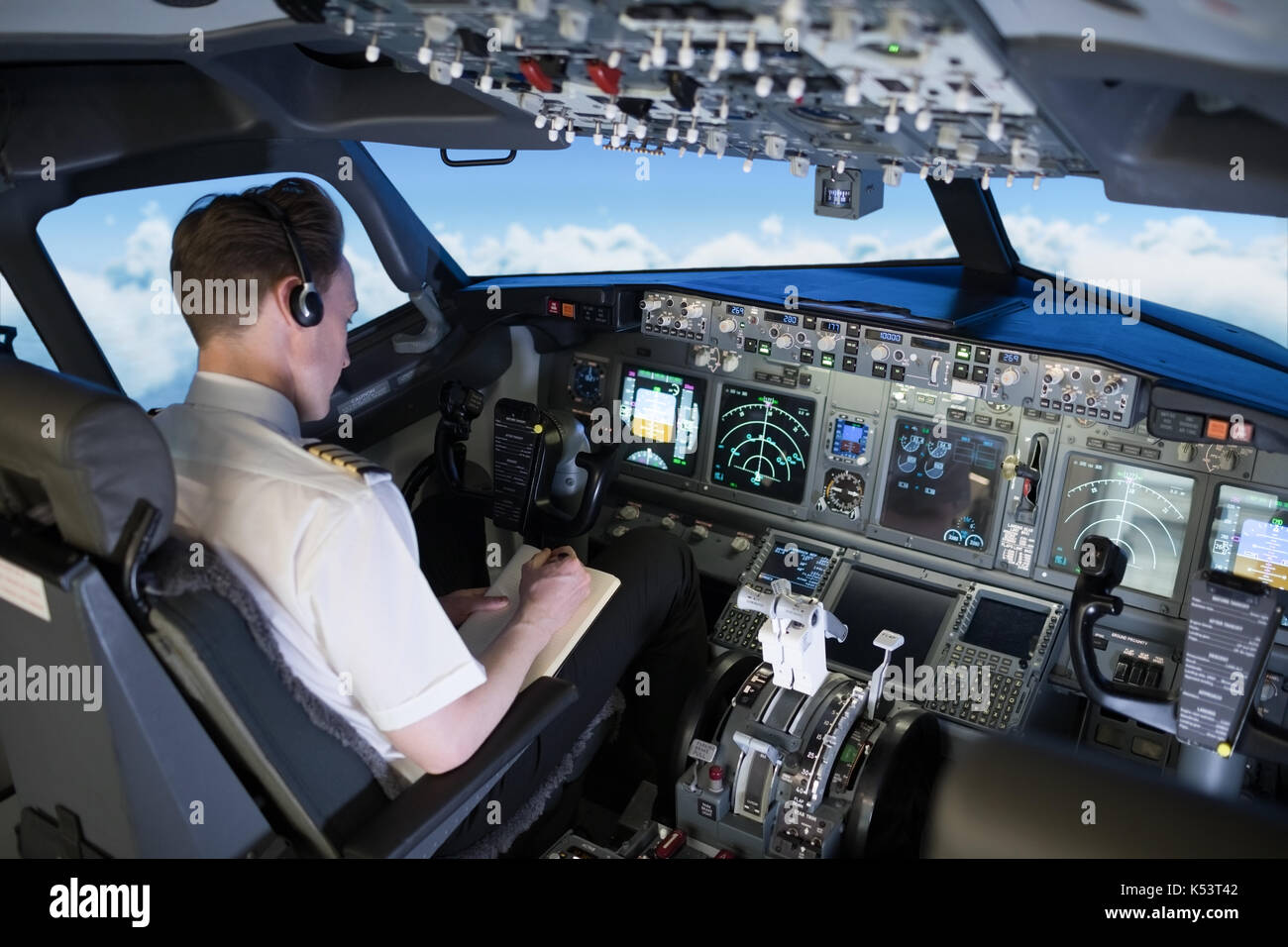 High angle view of young male pilot writing on book while sitting in ...
