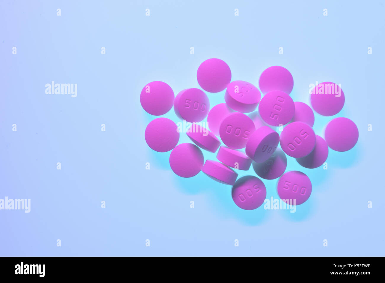 Pink Medication tablets, on blue surface Stock Photo - Alamy