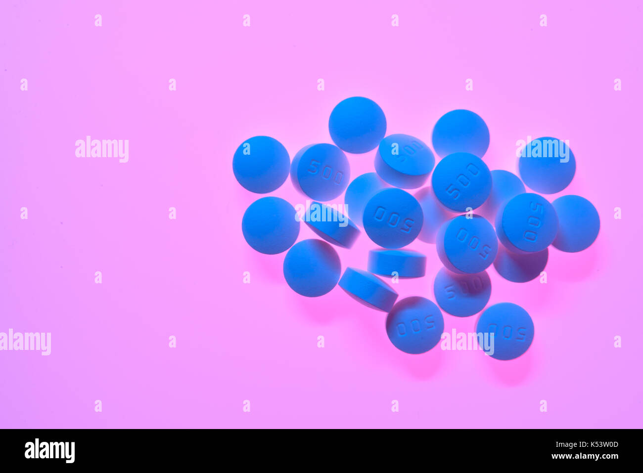 Blue Medication tablets, on pink surface Stock Photo - Alamy