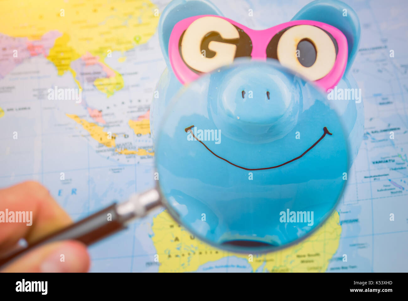 Happy piggy bank on the world map with magnifyed bright smile ready to ...