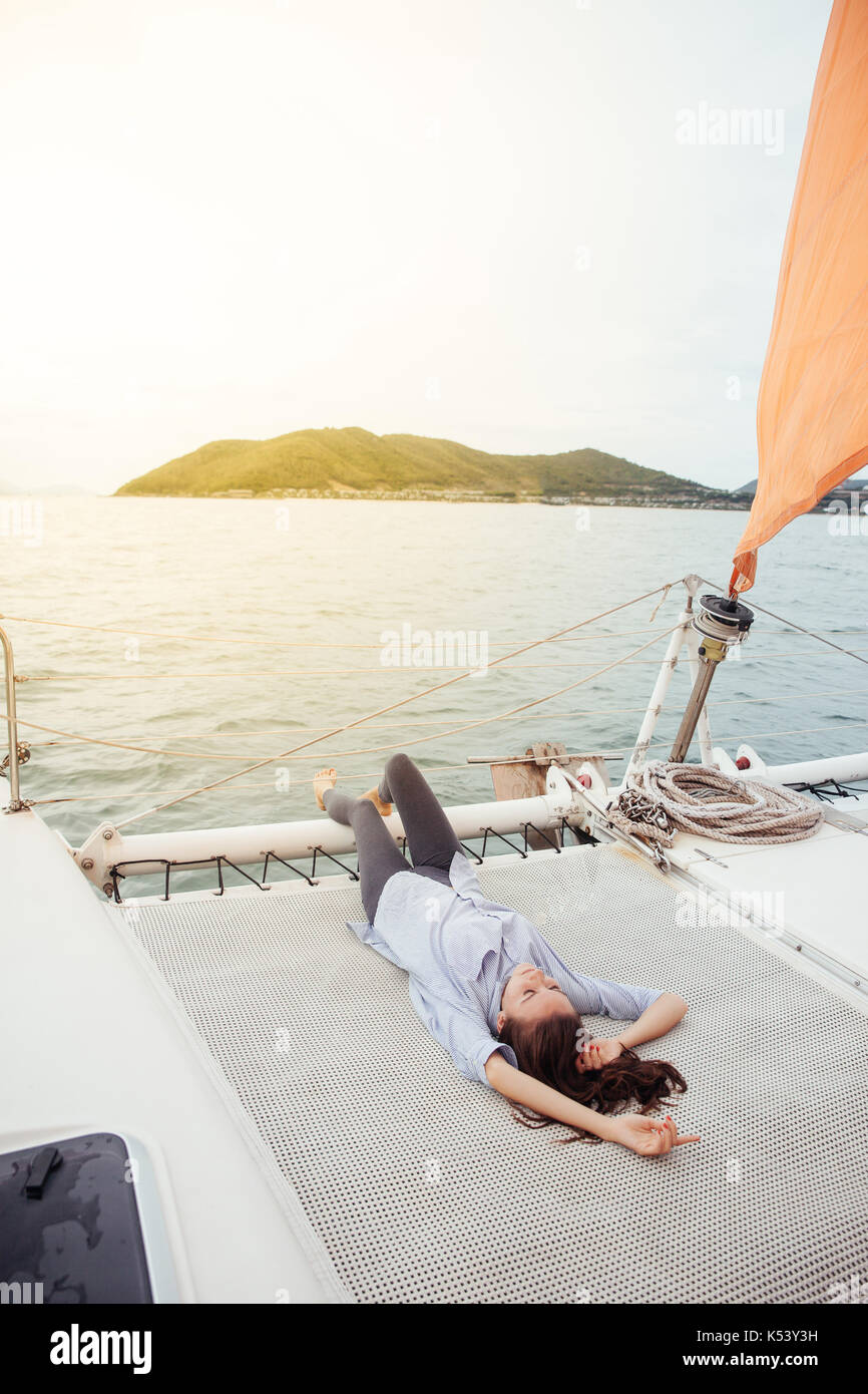 Young woman resting on ship deck while enjoying a cruise on a boat at ...