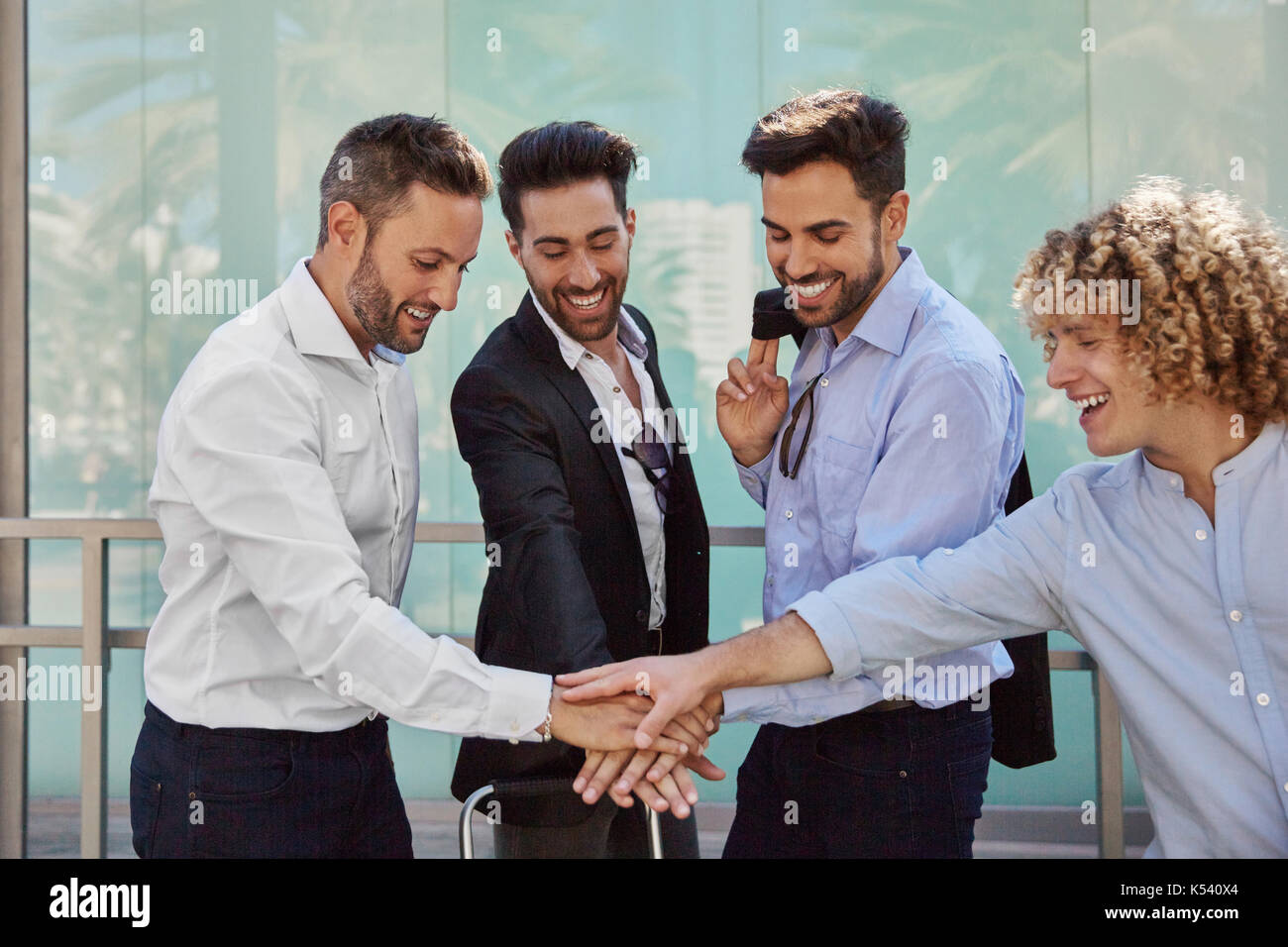 Portrait of young businessmen holding hands together in unity gesture ...
