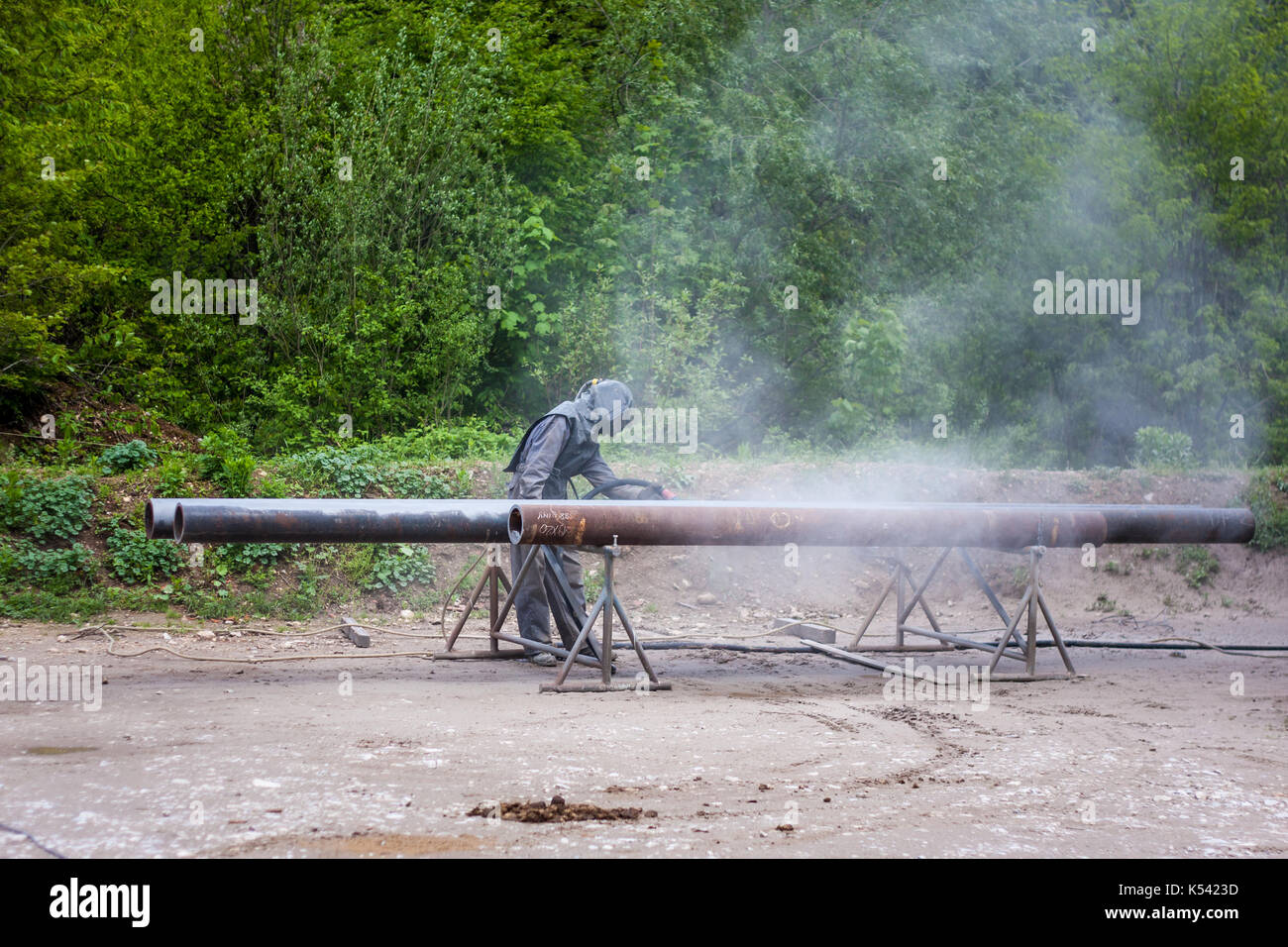 Sandblasting metal pipes outside Stock Photo - Alamy