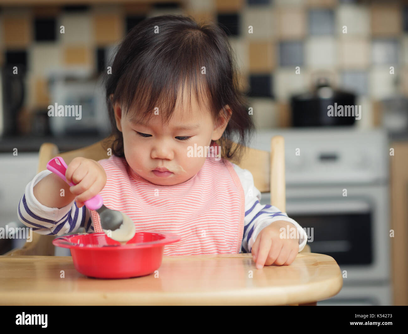 baby girl eating food at home Stock Photo - Alamy