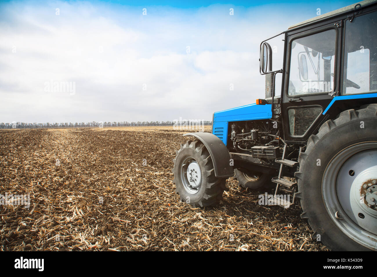 Old blue tractor in a empty field on a bright sunny day. Agricultural ...