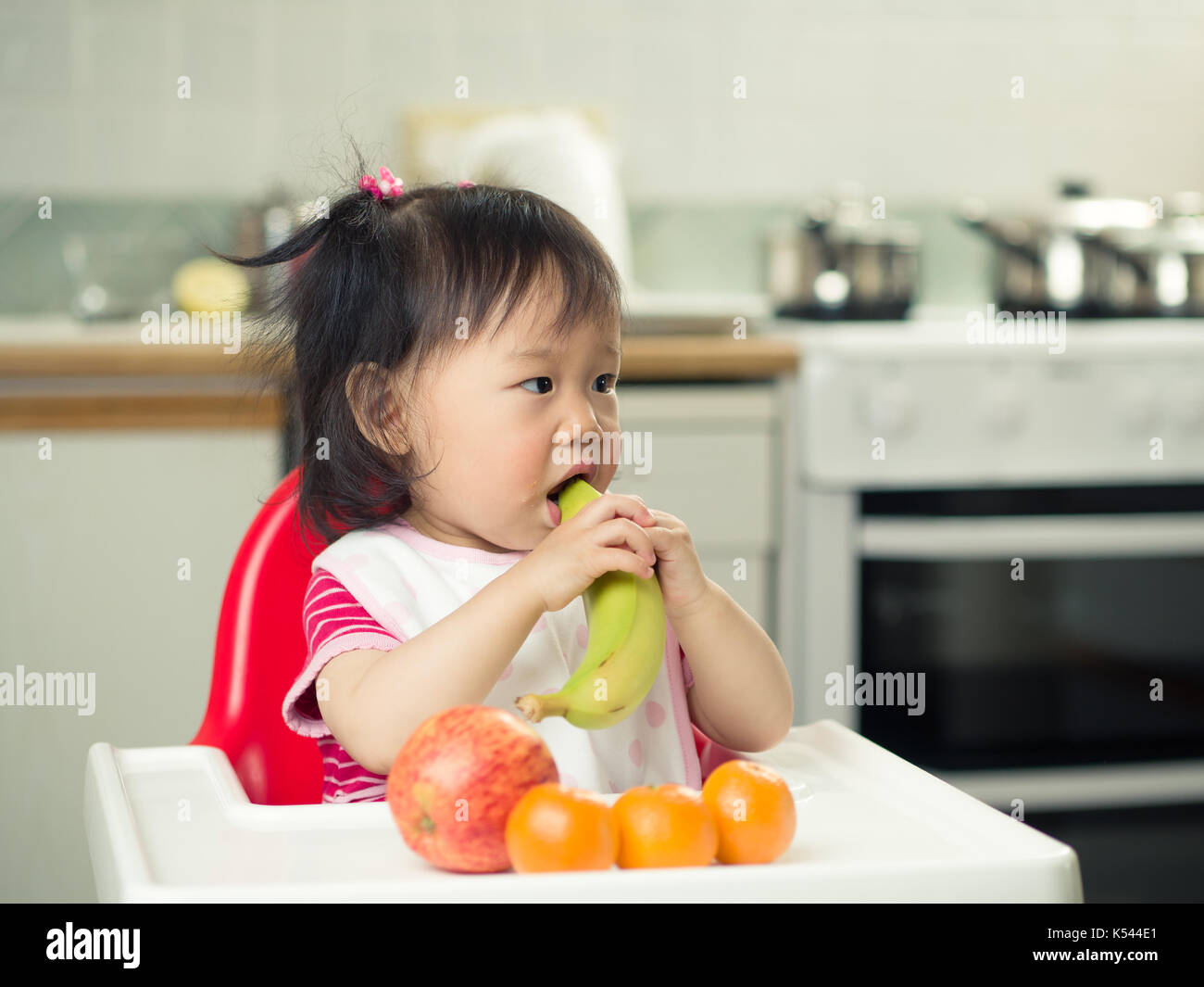 baby girl eating fruit at home Stock Photo - Alamy