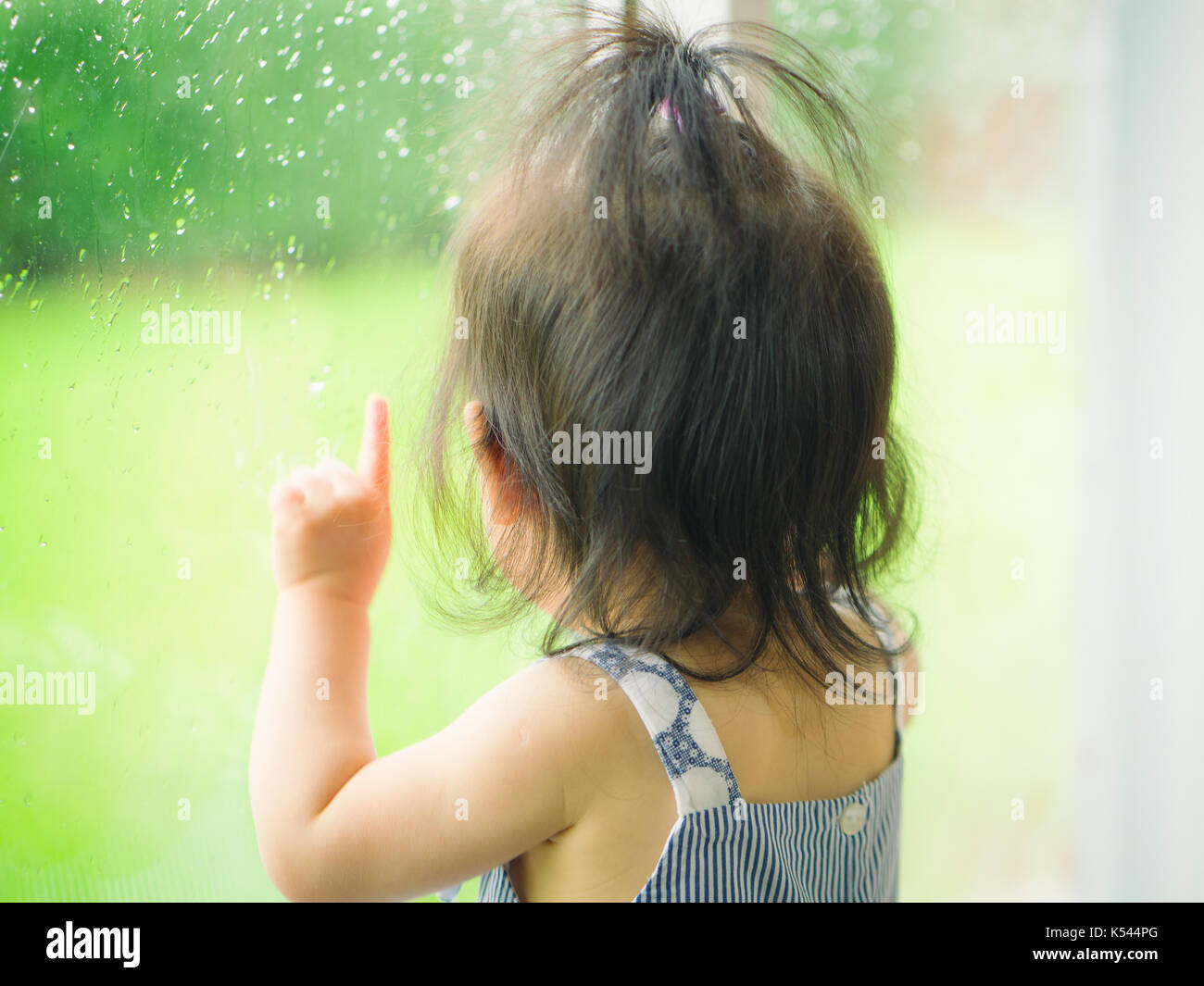 baby girl looking outside rainning Stock Photo - Alamy
