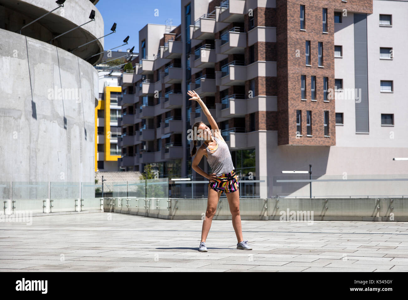 Young attractive woman exercise stretching in urban environment at ...