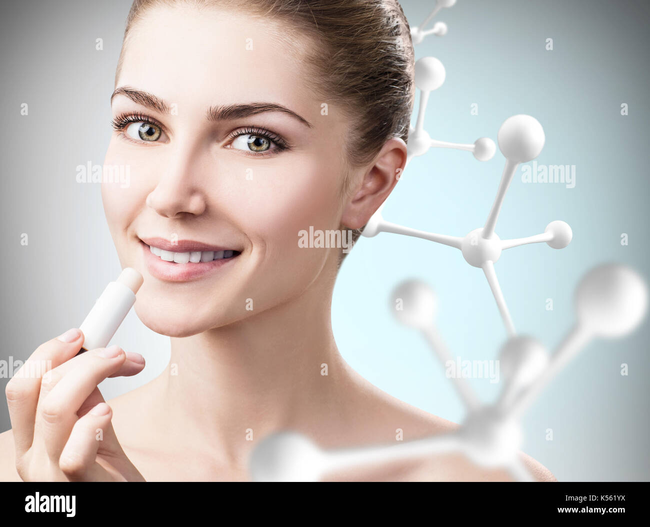 Beautiful young woman putting lipbalm in big molecules chain over gray background. Innovation ...