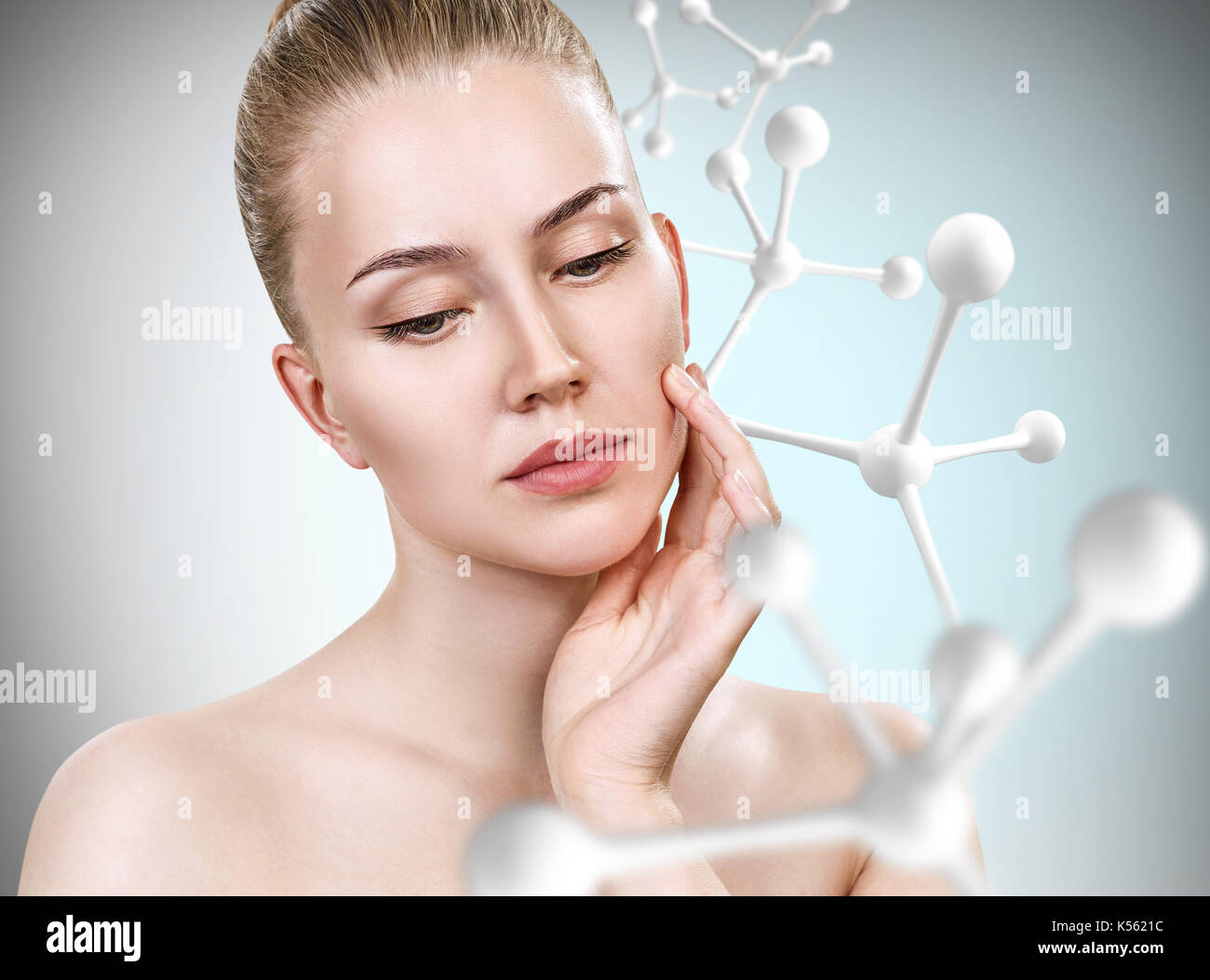 Beautiful young woman with big white molecule chain over gray background. Innovation cosmetics ...