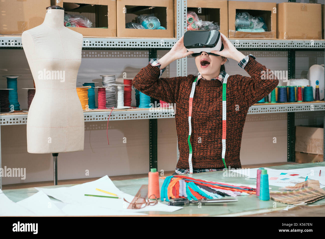 young beautiful female clothing maker using VR technology goggles ...