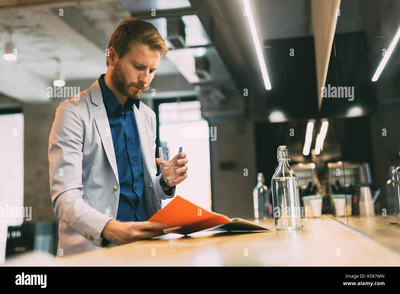 Businessman drinking water and reading paper Stock Photo - Alamy
