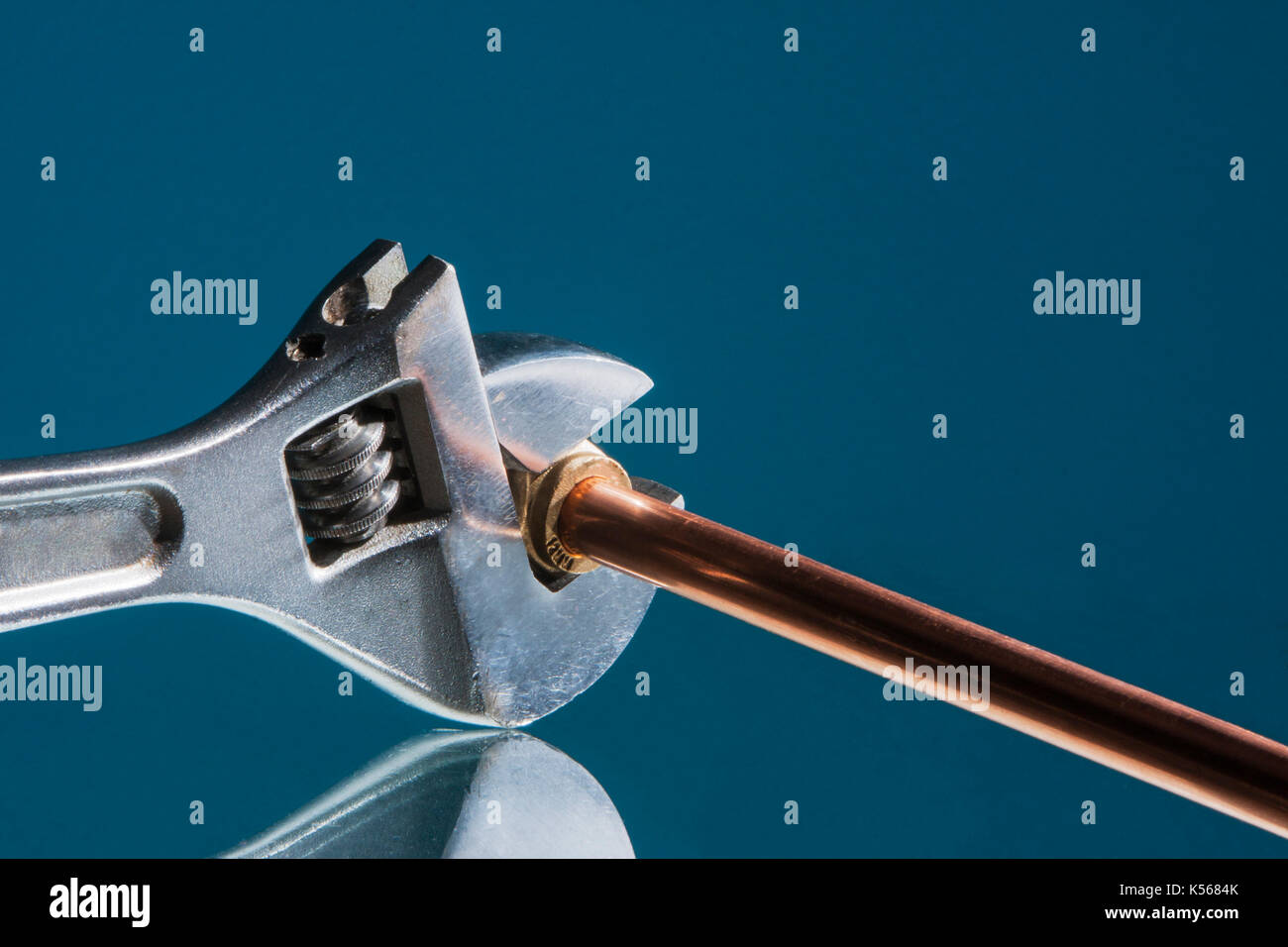 Plumber wrench for repairing a copper water pipe with a blue background ...