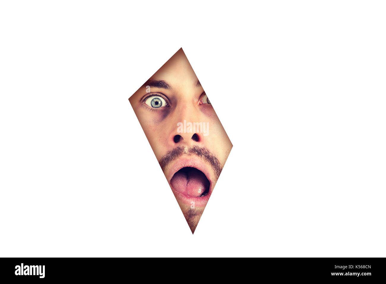 Portrait of a scared shocked man looking though a gap in a white paper ...