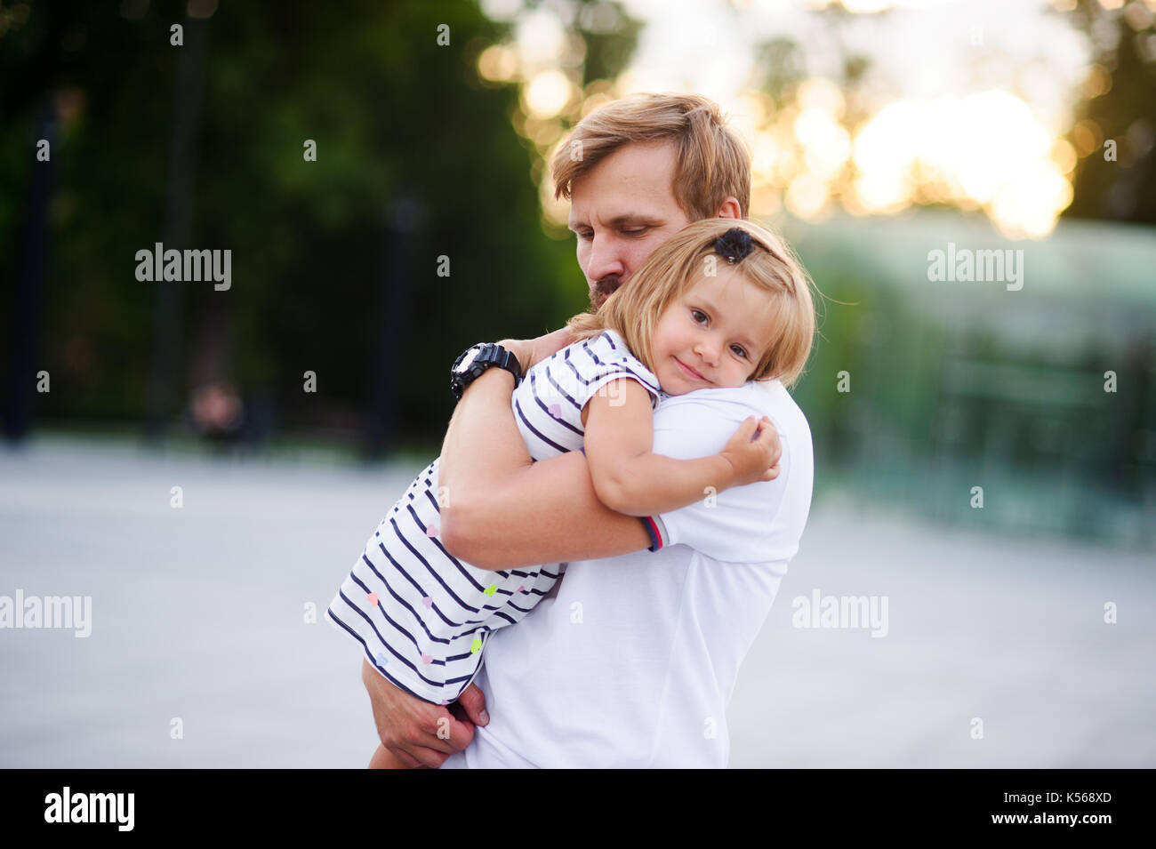 Young father holds the little daughter on hands. Man gently presses to ...