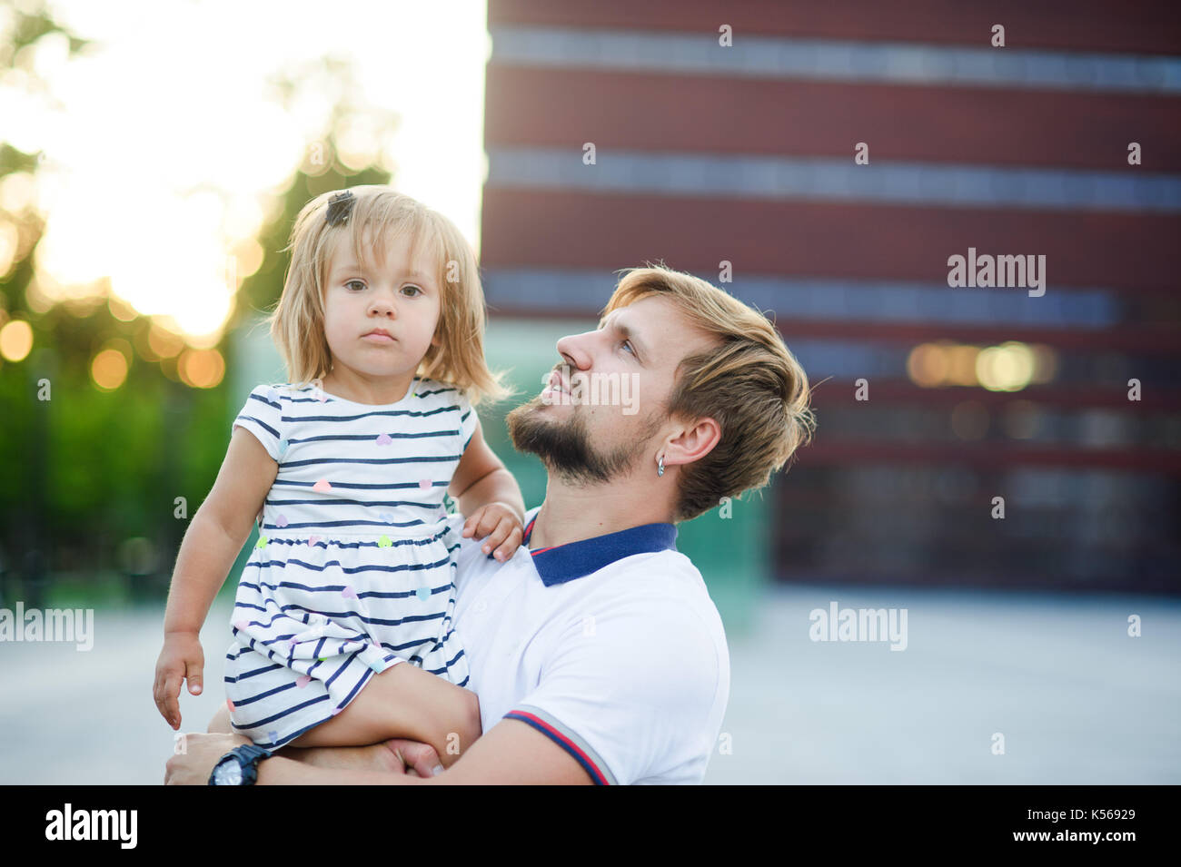 Young father holds the little daughter on hands. Man gently presses to ...
