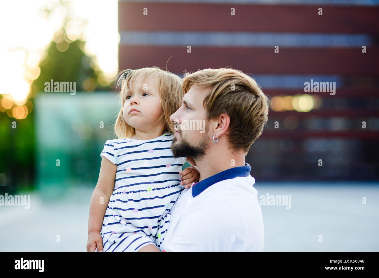 Young father holds the little daughter on hands. Man gently presses to ...