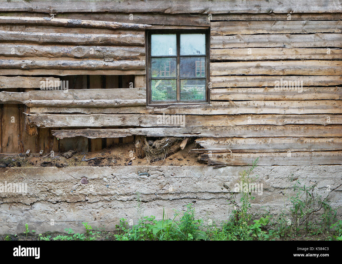 The rotten wooden wall of a village barn with a simple abandoned window ...