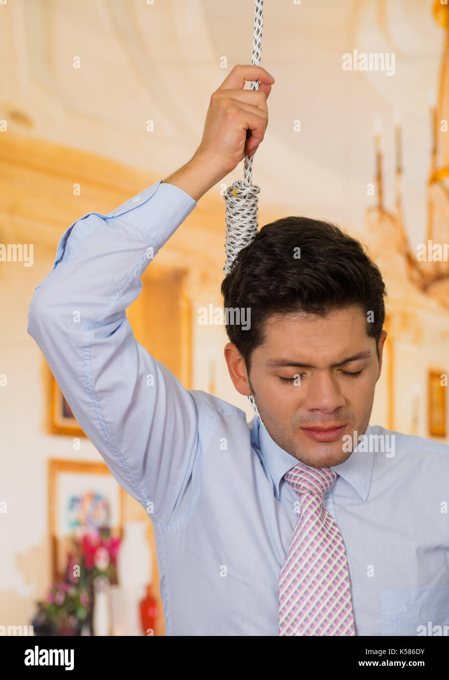 Depressed man with a noose around his neck, back view in a room ...