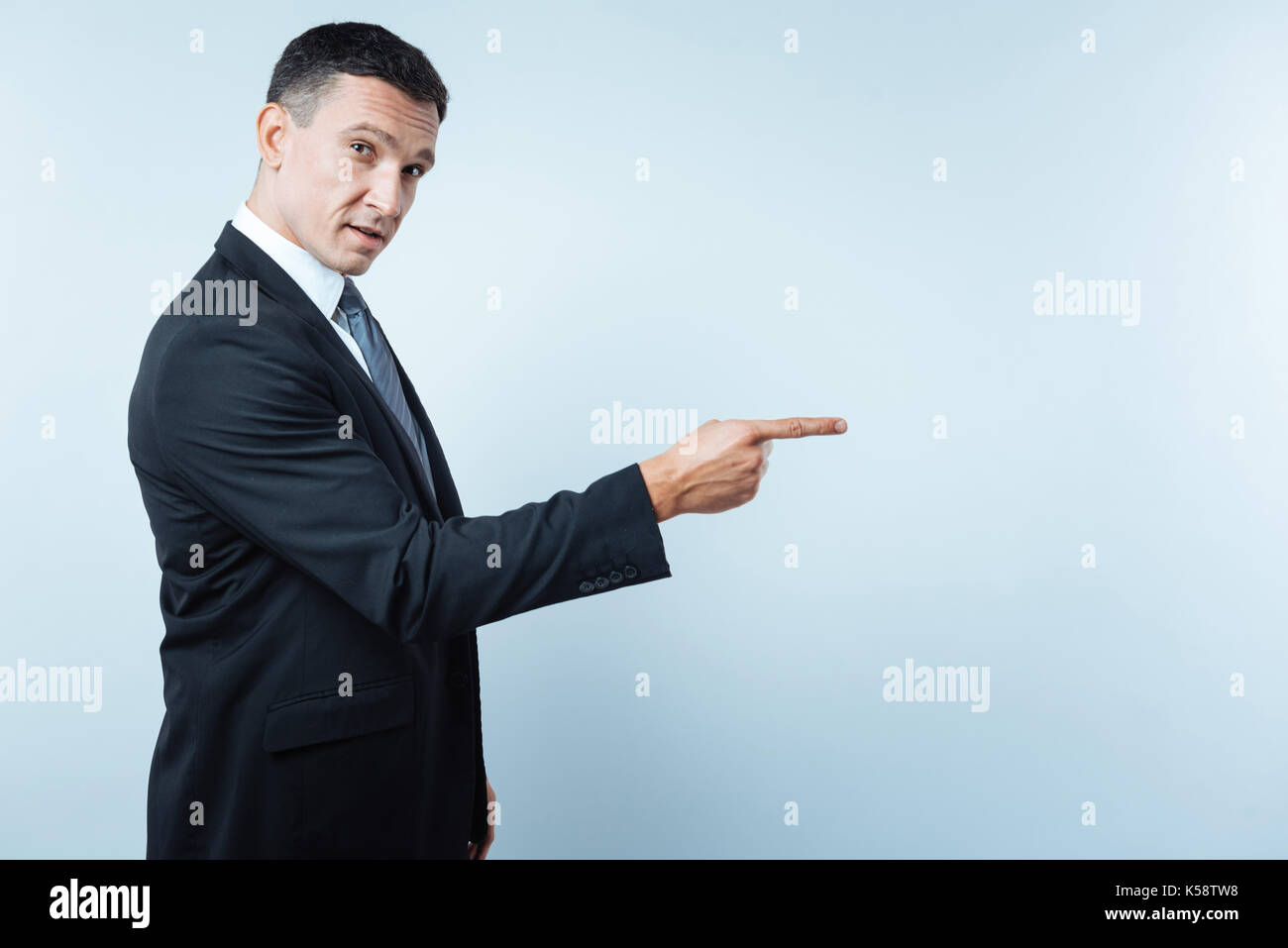 Handsome nice entrepreneur pointing in front of him Stock Photo - Alamy
