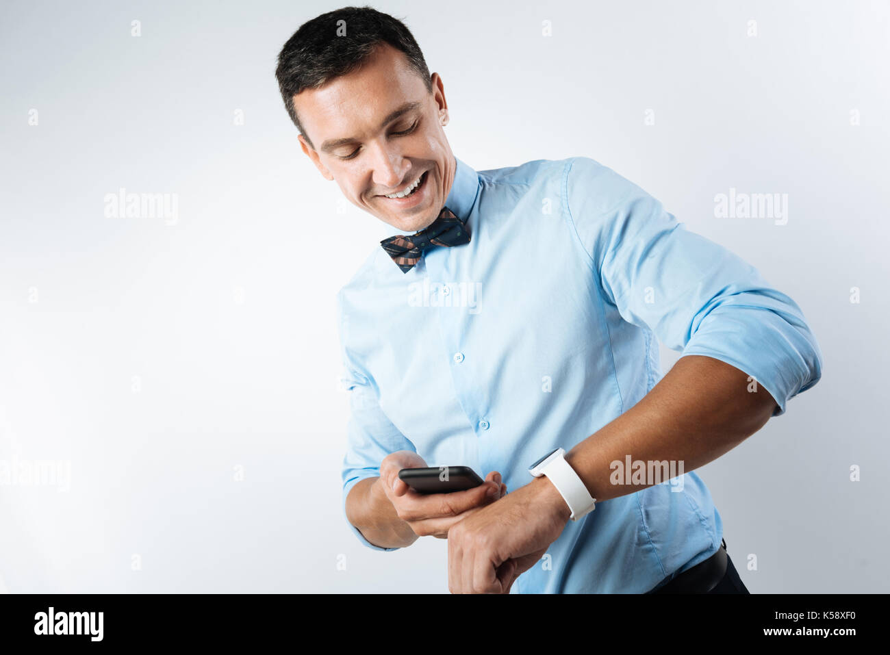 Positive young man looking at his smartwatch Stock Photo - Alamy