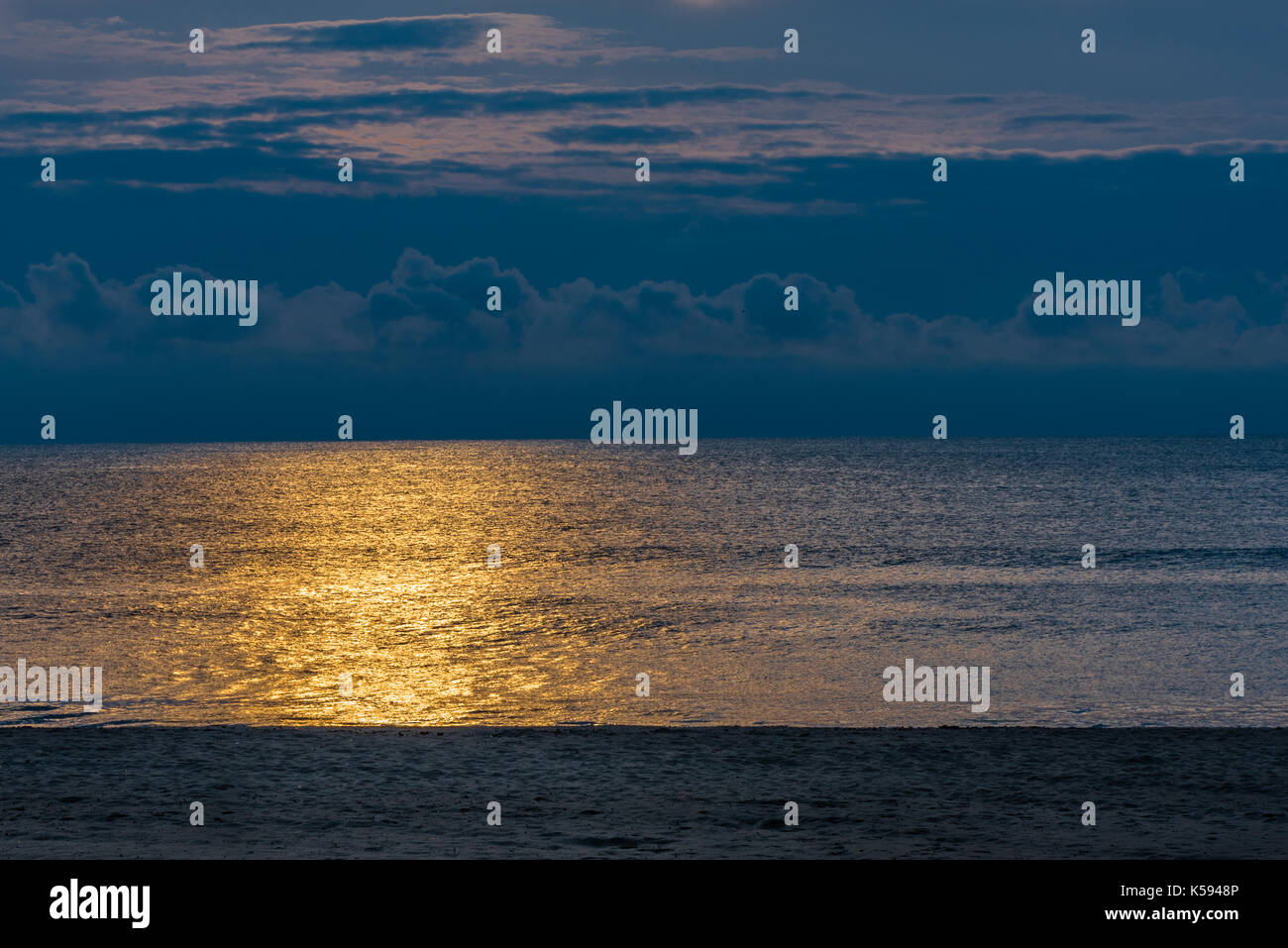 The Spring Lake beach reflects the golden glow of the sun early in the ...