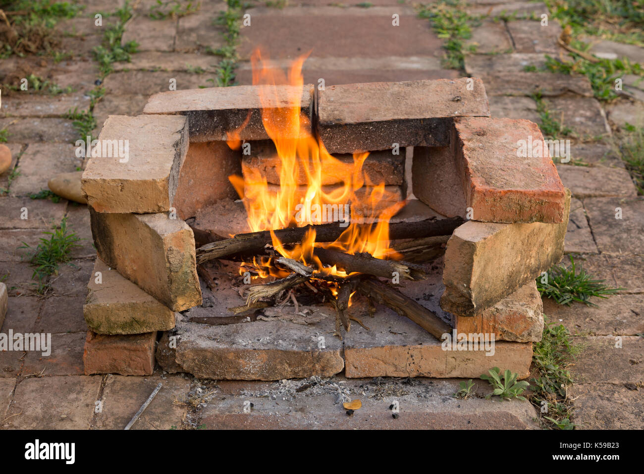 Flames burning wood in stove made from brick improvised on the floor ...
