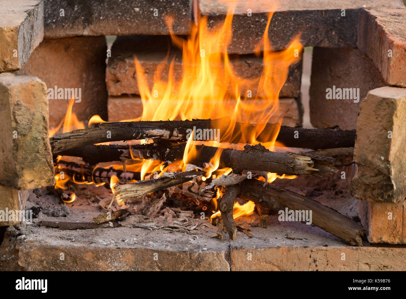 Flames burning wood in stove made from brick improvised on the floor ...