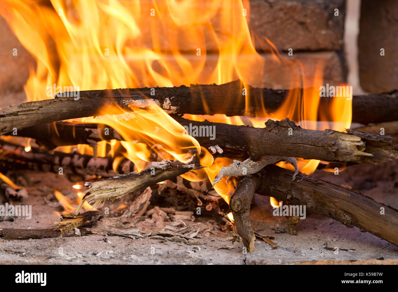 Flames burning wood in stove made from brick improvised on the floor ...