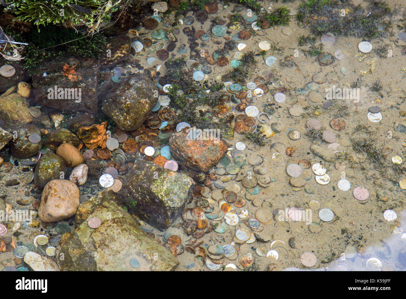 Coins thrown into a wishing well Stock Photo - Alamy